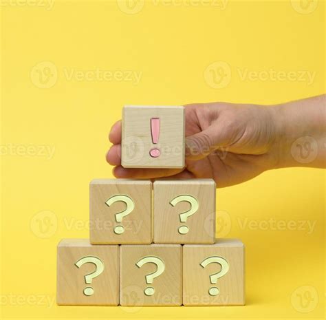 Hand Hold Wooden Cube With Exclamation Marks And A Question Mark On A