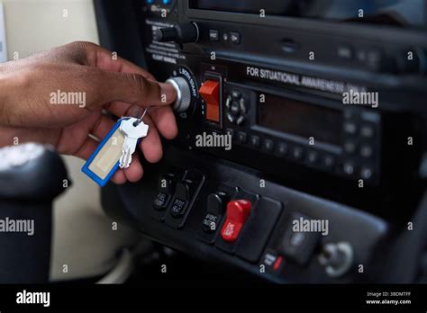Pilot Inserting Key In Ignition Switch Of Aircraft Cockpit Panel Stock