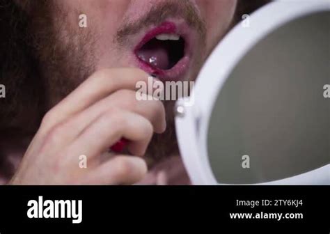 Extreme Close Up Of Male Hand Applying Red Lipstick On One Side Of