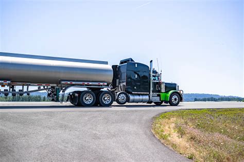 탱크 세미 트레일러에서 액체화물을 운반하는 녹색 펜더가 있는 블랙 클래식 빅 리그 세미 트럭 트랙터는 평평한 고속도로 도로에서 운전합니다 0명에 대한 스톡 사진 및 기타