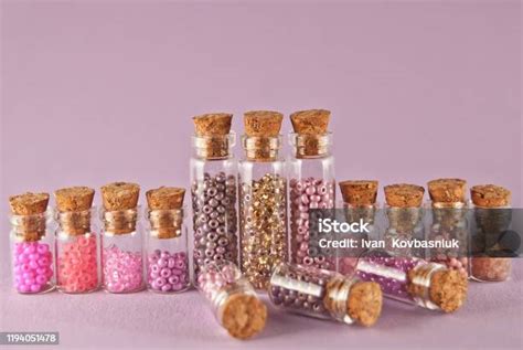 밝은 보라색 배경에 유리 항아리에 베이지 색 분홍색과 노란색 구슬 나무 코르크투명 용기에 구슬 질서 균형과 혼돈의 개념 0명에