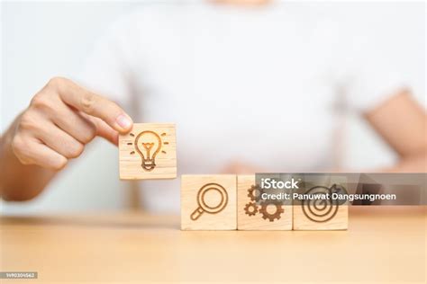 다트판 위에 전구를 들고 있는 여자의 손 기어 돋보기 아이콘 블록 사고 사업 계획 프로세스 목표 전략 목표 사명 행동 연구 팀워크 및 아이디어 개념 개념에 대한 스톡 사진