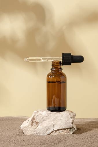 밝은 갈색 베이지 색 배경에 모래가있는 돌에 어두운 유리 화장품 병을 엽니 다 천연 유기농 스파 안티 에이지 화장품과 새로운 자연주의 개념 정면보기 공간을 복사합니다 0명에