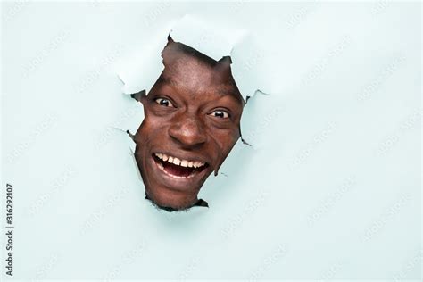 Handsome Young Black Man With Head Through A Cardboard Paper Looking