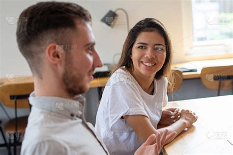 积极的青年男女坐在桌旁聊天