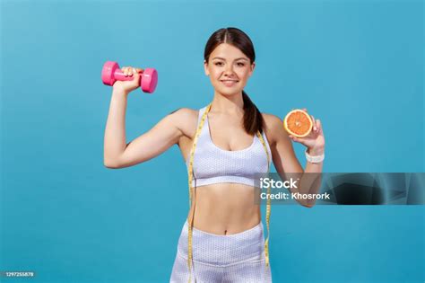 아령과 자몽의 절반을 들고 어깨에 테이프 측정을 가진 미소 슬림 한 여자 스포츠에 가서 몸에 여분의 센티미터를 줄이기 위해 다이어트를 유지 25 29세에 대한 스톡 사진 및