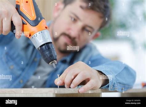 Man Is Assembling Furniture Drilling Metal Guides To The Board Stock