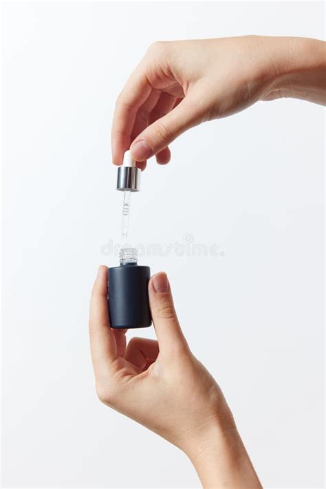 Two Hands Holding A Small Bottle With A Dropper On A White Background