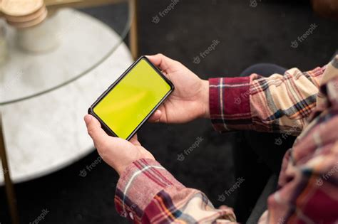 Человек, использующий мобильный телефон горизонтально с цветным зеленым ...