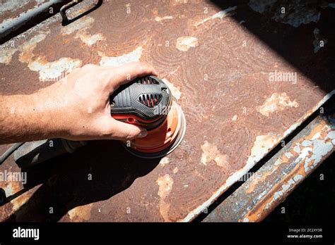 Man S Hand Operates A Disc Orbital Sander To Remove Paint And Rust From Metal Doors Stock Photo