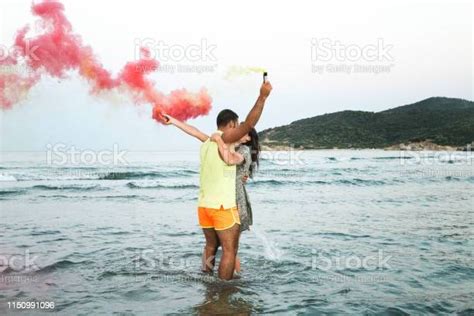 젊은 부부는 모래에 서 서 연기 폭탄을 들고 해변에 노란 색상과 붉은 색 연기 폭탄 로맨틱 커플 2명에 대한 스톡 사진 및 기타 이미지 Istock