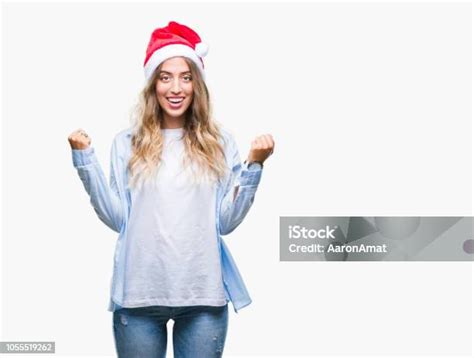 축 하 하는 고립 된 배경 위에 크리스마스 모자를 입고 아름 다운 젊은 금발의 여 자가 놀란 고 제기 하는 무기와 성공을 위한 놀라게 했 고 눈 우승자 개념입니다 겨울에