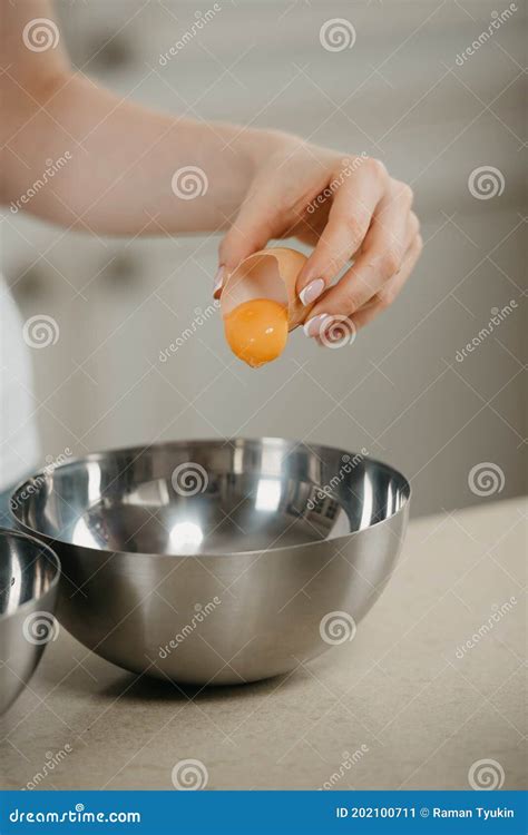 The Hands Of A Woman Who Is Separating The Egg White From The Yolk Above A Bowl Stock Image