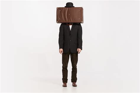 흰색 스튜디오 배경 위에 고립 된 서류 가방으로 얼굴을 덮고있는 갈색 양복을 입은 세련된 남자의 초상화 25 29세에 대한 스톡