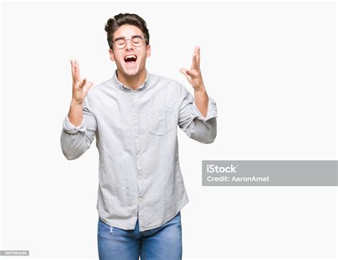 미친 미친 무기와 성공을 위한 축 하 하는 고립 된 배경 위에 안경을 쓰고 잘생긴 젊은이 제기 하 고 흥분 비명 눈을 폐쇄