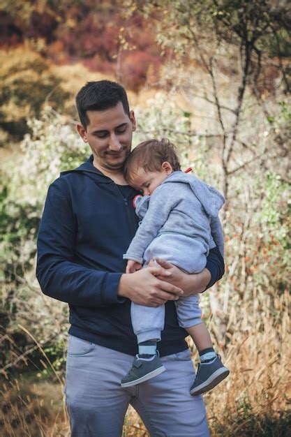 Padre Llevando A Su Hijo Dormido Mientras Está De Pie En El Bosque