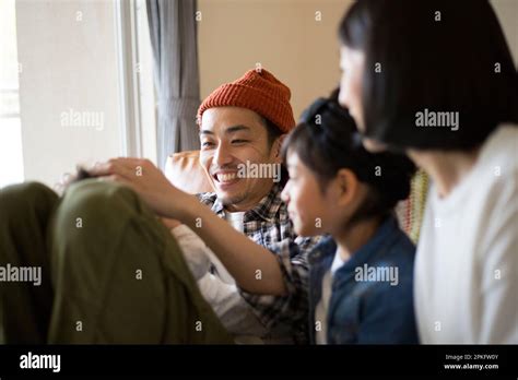 A Father Holding His Baby On His Lap While His Older Babe And Mother Watch Stock Photo Alamy
