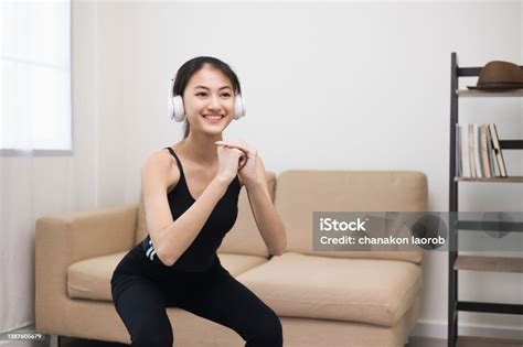 젊은 아름 다운 피트 니스 아시아 여자 스쿼트를 하 고 집에서 운동 운동 앉아 매력적인 여성 워밍업 몸 훈련 착용 스포츠웨어 사이드 뷰 스포티 한 소녀는 따뜻하게 심장 몸을