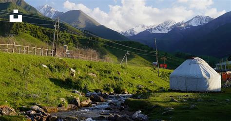 낮에는 산 근처의 푸른 잔디밭에 있는 하얀 텐트 사진 Unsplash의 무료 키르기스스탄 이미지