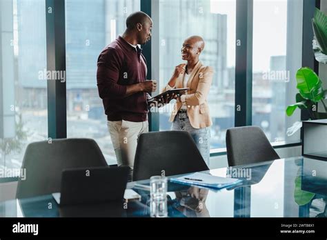 Two Professionals Collaborate And Discuss Ideas In A Modern Office They Use A Tablet During
