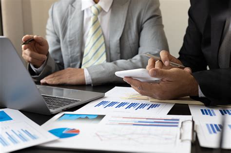 재무 고문은 사업가와 함께 일하면서 사무실 책상에서 데이터를 계산하고 분석합니다 2명에 대한 스톡 사진 및 기타 이미지 2명