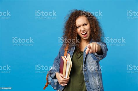 데님 옷에 젊은 슬픈 아프리카계 미국인 소녀 사춘기 학생 배낭은 파란색 배경 스튜디오 초상화에 고립 된 책을 보유 고등학교 대학 대학 개념에서 교육 복사 공간을 모의 합니다