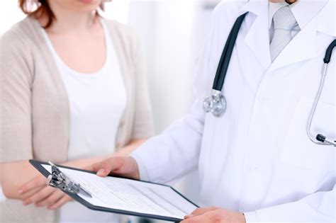 Close up de um médico do sexo masculino segurando um formulário de inscrição ao consultar o