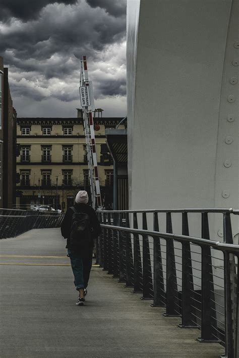 낮에는 회색 콘크리트 바닥에 서 있는 검은색 재킷과 검은색 바지를 입은 여자 사진 Unsplash의 무료 방책 이미지