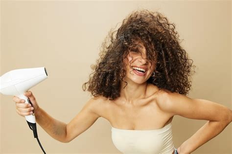 Premium Photo Woman Dries Curly Afro Hair With Blow Dryer Home Beauty