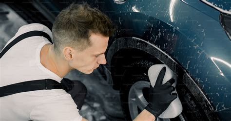 손으로 세차 세차 서비스에서 스펀지로 현대 파란색 자동차의 바퀴를 씻는 청년의 최고 각도 보기 사진 Unsplash의