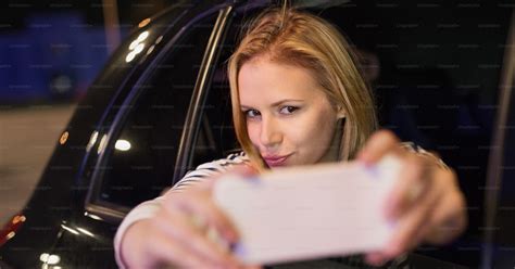 밤에 현대식 차를 타고 도시에 있는 아름다운 젊은 여성 스마트폰을 들고 셀카를 찍는다 사진 Unsplash의 자동차 이미지