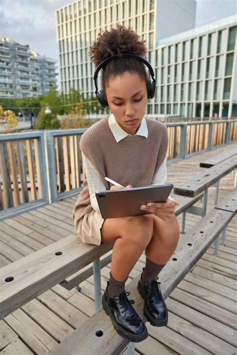 城市高清图片 卷发女学生远程作业使用数字平板电脑和手写笔通过耳机听音乐，穿着随意，坐在城市环境的户外现代学习技术 产品实拍免费下载 格式 编号53089878 千图网