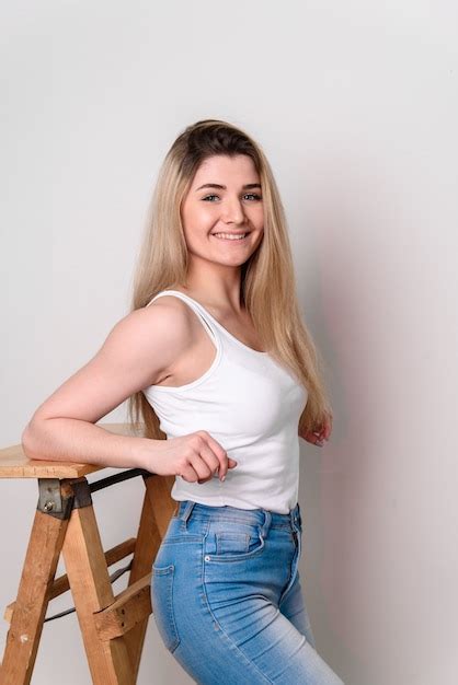 Premium Photo Красивая девушка в белой майке и джинсах улыбается
