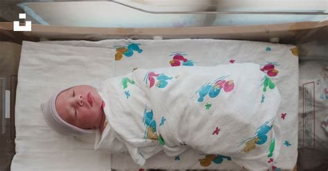 흰색과 빨간색 꽃무늬 옷을 입은 아기가 침대에 누워 있습니다 사진 Unsplash의 무료 신생아 이미지