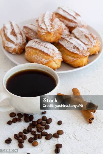 흰색 테이블에 접시에 집에서 만든 바닐라 에클레어 또는 이익 복사 공간을 복사합니다 커피 콩과 아니스 스타 흰색 테이블에 계피 스틱 전통적인 프랑스 맛있는 디저트와 커피 컵