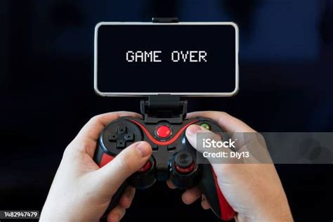게이머는 스마트폰에서 게임을 합니다 검은 배경에 전화기가 있는 조이스틱을 가진 손 비디오 게임에 대한 스톡 사진 및 기타 이미지 비디오 게임 게임 오버 문구 손