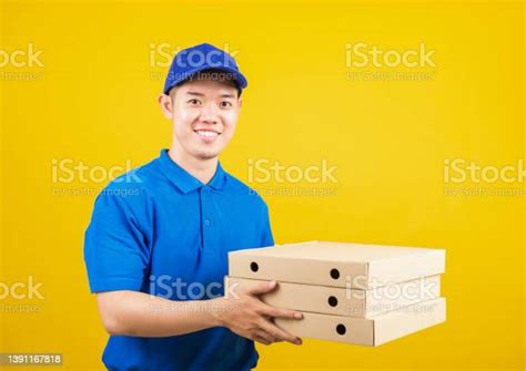 배달 서비스 남자 서 그는 파란색 티셔츠와 모자 유니폼을 입고 미소 음식 주문 피자 골판지 상자를 제공 모자 모자류에 대한 스톡