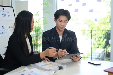 Professional Business Team Analyzing Data On Digital Tablets And Discussing Strategies At Modern