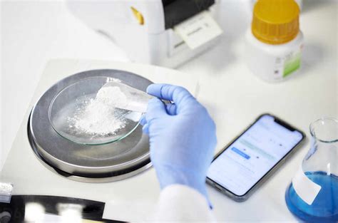 Hand Of Scientist Measuring Chemical On Weighing Scale In Laboratory Stock Photo