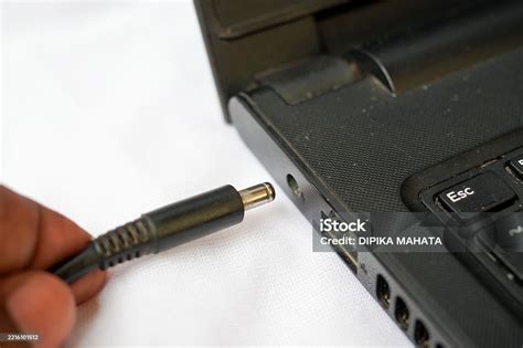 남자의 손은 전원 공급 장치 어댑터 코드를 일반 랩톱 컴퓨터 전원 입력에 연결하고 20 볼트 충전기로 랩톱의 배터리를 충전하는 추상적 인 개념 기호 한 사람 한 사람 선택적