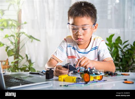 Asian Kid Babe Plugging Energy And Signal Cable To Sensor Chip With Arduino Robot Car Stock Photo