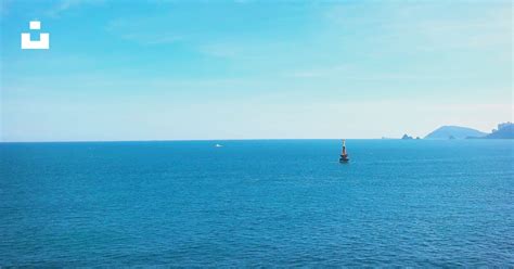 낮 동안 푸른 하늘 아래 푸른 바다에 서 있는 검은 셔츠를 입은 사람 사진 Unsplash의 무료 파랑 이미지