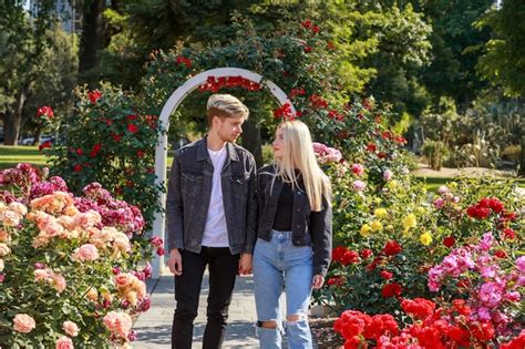Una Pareja Joven Se Para En Medio De Las Rosas En El Parque Foto Premium
