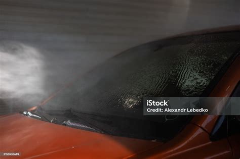 압력 물총으로 자동차 앞 유리를 씻는 클로즈업 세차장에서는 강력한 물 분사로 앞유리에서 거품과 남아 있는 먼지를 씻어냅니다 고압 청소에 대한 스톡 사진 및 기타 이미지