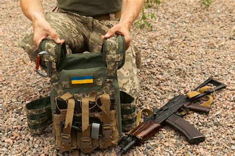 위장 전술 제복을 입은 군인과 나무와 녹지를 배경으로 한 군용 방탄복 전투 꽁초가 달린 방탄복 우크라이나 군대 군사 개념입니다 전쟁이 없습니다의료 지혈대 개인 장식품에 대한