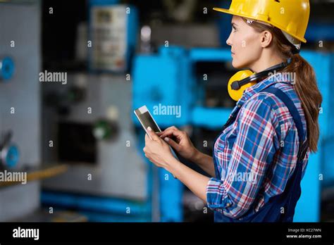 Side View Portrait Of Female Machine Operator Using Digital Tablet While Working With Machines