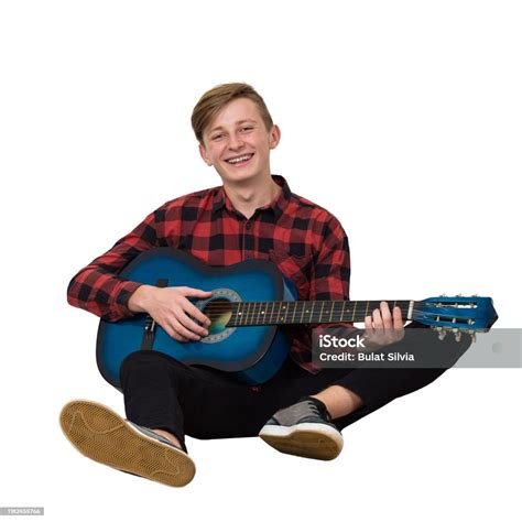 흰색 배경 위에 고립 된 바닥에 앉아 어쿠스틱 기타에서 연주 재능있는 소년 십대의 전체 길이 초상화 학생들이 유명한 뮤지션이 될