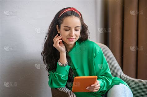 穿着绿色衬衫的年轻女子聚精会神地看着床单。