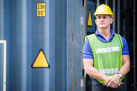 노란 안전 헬멧을 착용한 젊은 자신감 있는 백인 남성 엔지니어와 화물화물 선에서 화물 컨테이너 박스를 수입 및 수출 운송에 대한 제어 적재 컨테이너 상자 확인 건설업자에