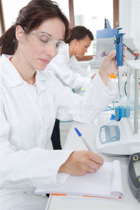 female scientist making notes as she conducts experiment stock image